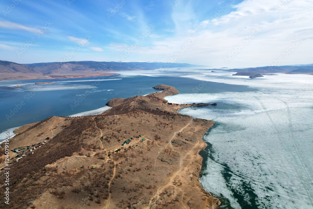 Stunning aerial view of the frozen lake in spring, surrounded by hills ...