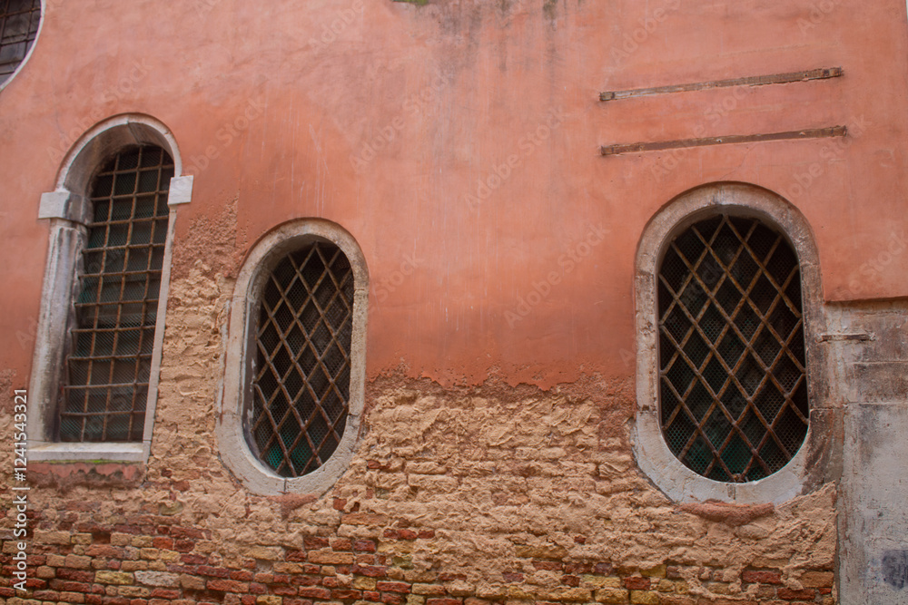 Facade of an old Italian brick house with square and rounded windows ...
