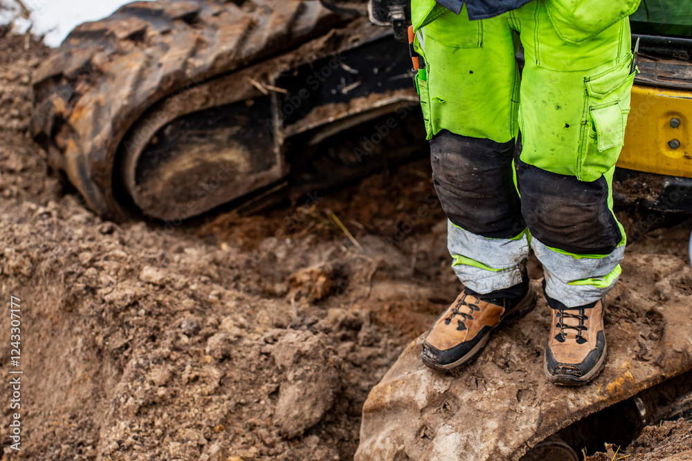 Industrial construction worker boots standing on mini excavator in ...
