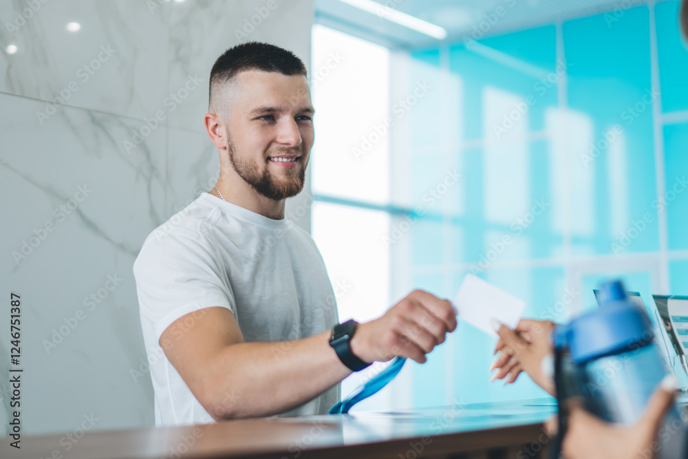 Handsome caucasian man receptionist in gym greeting female client ...