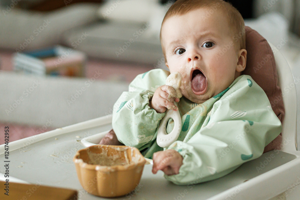 Cute little baby try to eat solid food in child chair. Complementary ...