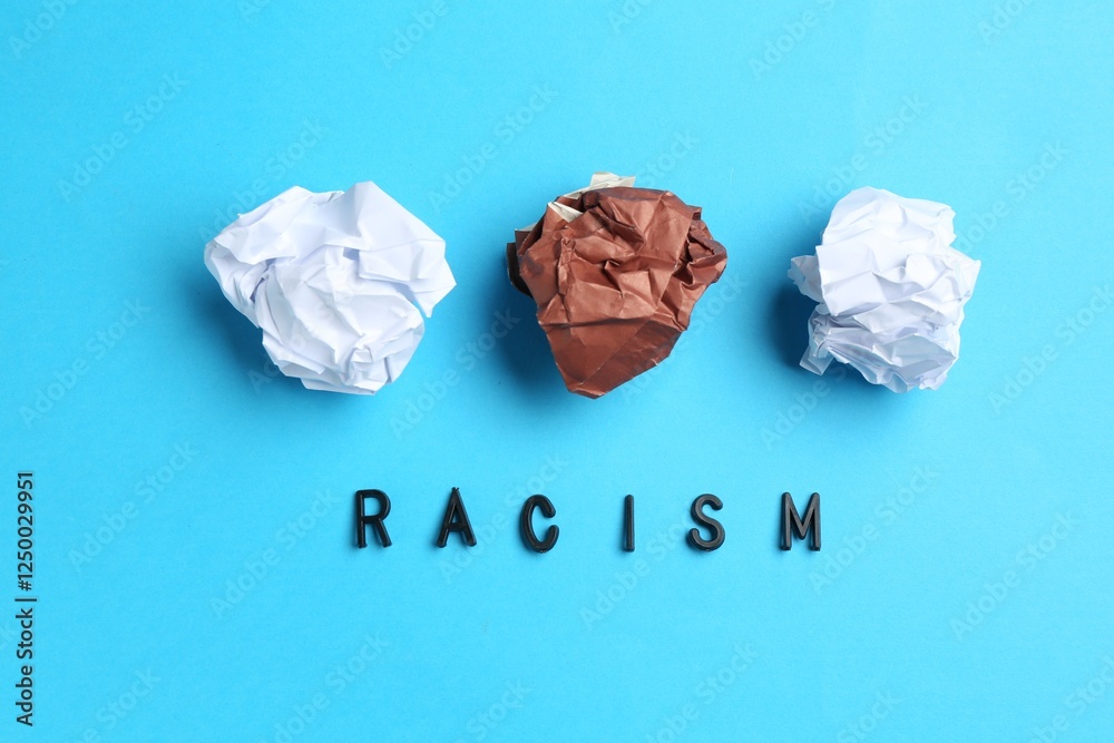 Word Racism and crumpled paper pieces of different colors on light blue ...