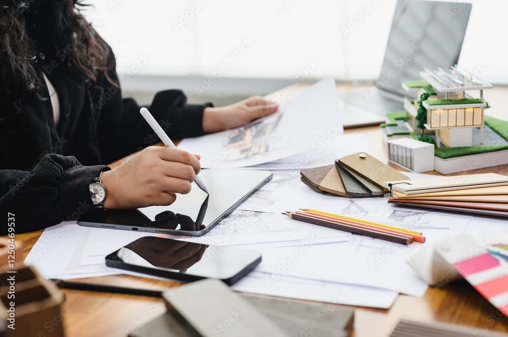Architect uses tablet while reviewing interior drawing and material ...