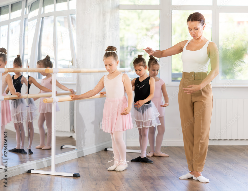 Girl students of choreographic school look at woman teacher and repeat ...