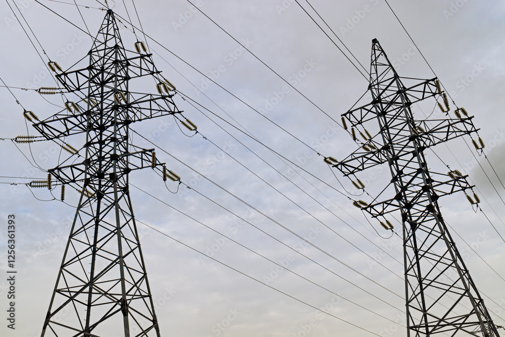 High-voltage electricity transmission towers against cloudy sky with ...