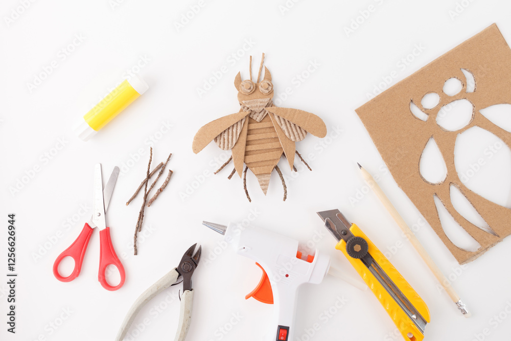 Handmade cardboard insect crafts with crafting tools on white ...