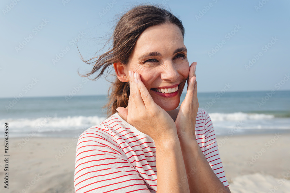 Beautiful woman touching cheeks at beach Stock Photo | Adobe Stock