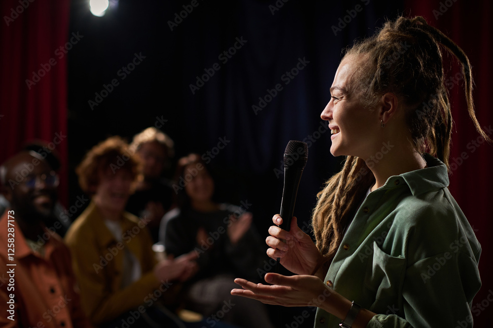 Person delivering stand-up comedy performance on stage with microphone ...