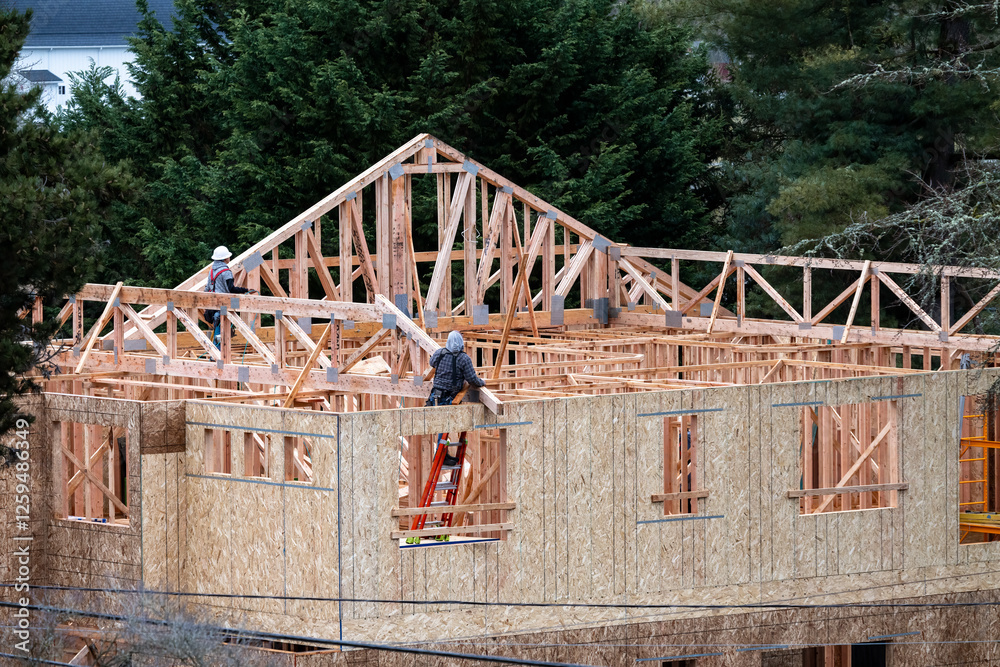 Workman on a ladder on second floor of new home under construction ...