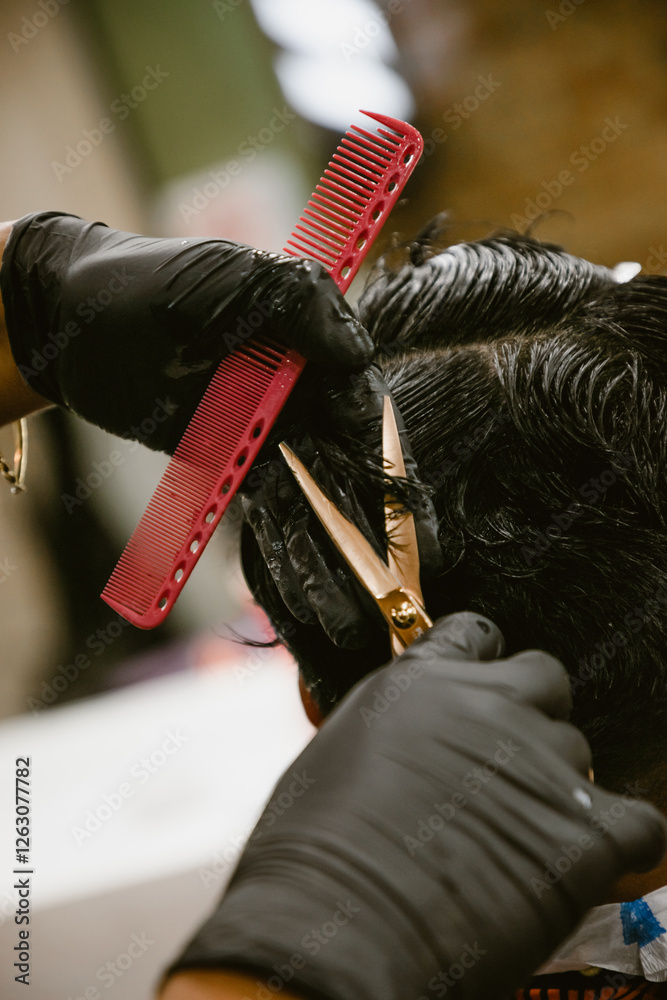 Primer plano de un barbero cortando el cabello con tijeras doradas y un ...