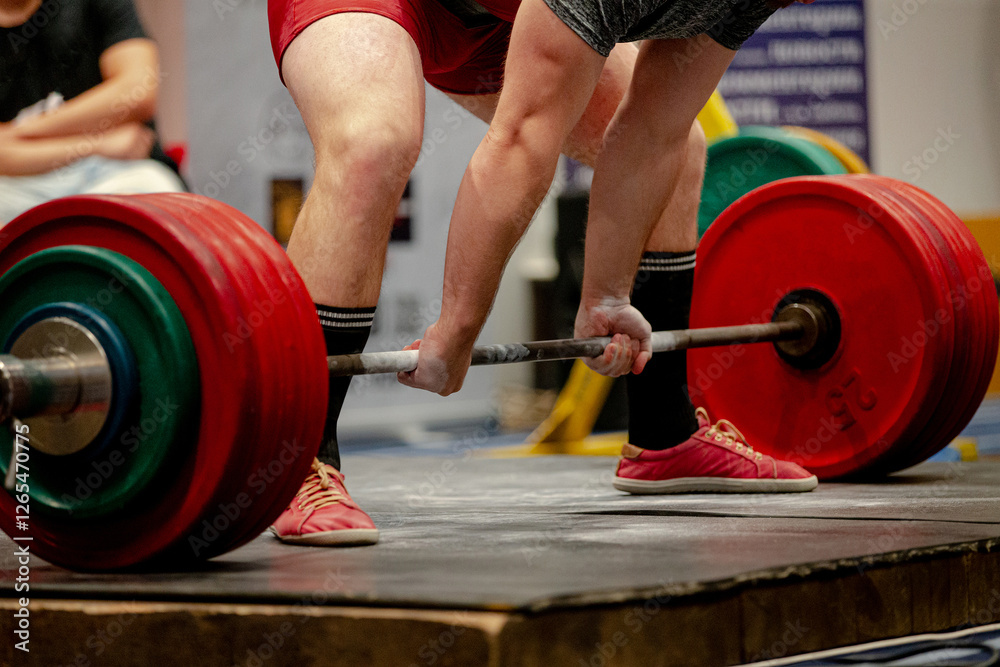 strong athlete focuses on lifting heavy barbell during deadlift ...