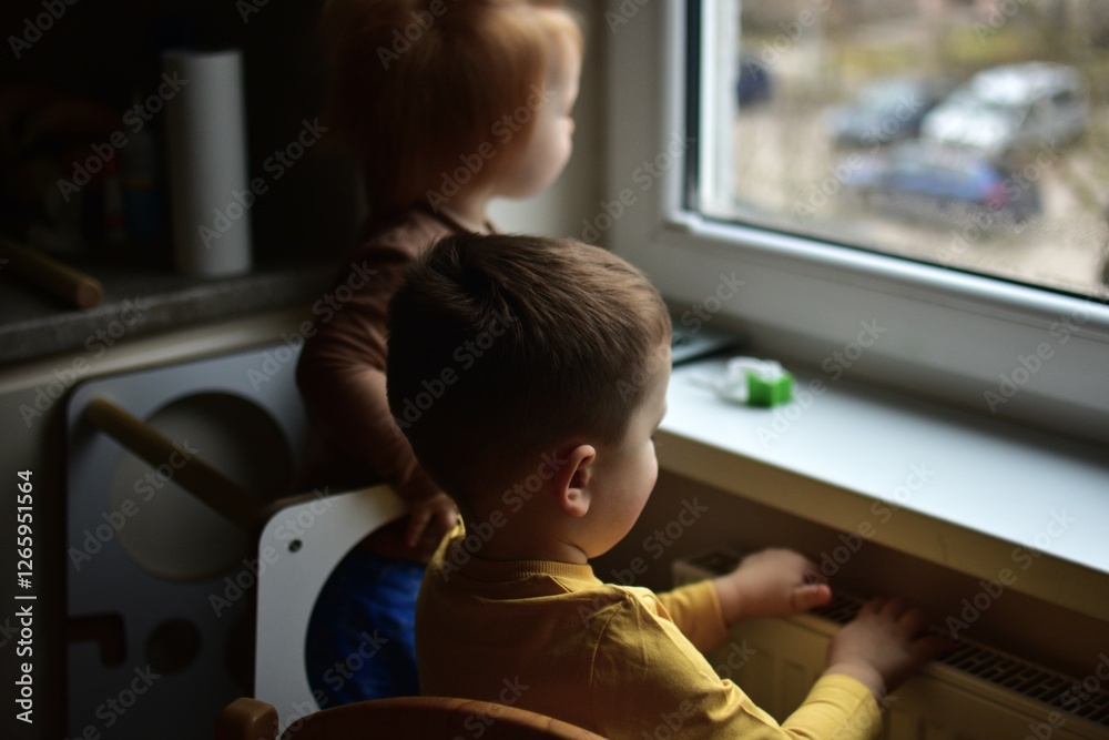 Toddler boy and girl curiously looking through the window. Brother and ...
