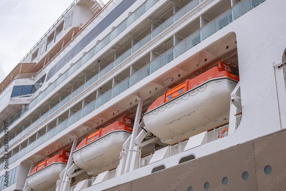Large cruise ship with lifeboats docked at port, showing safety ...