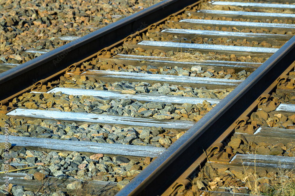 Metal railway tracks are lined with gravel, stretching across the ...