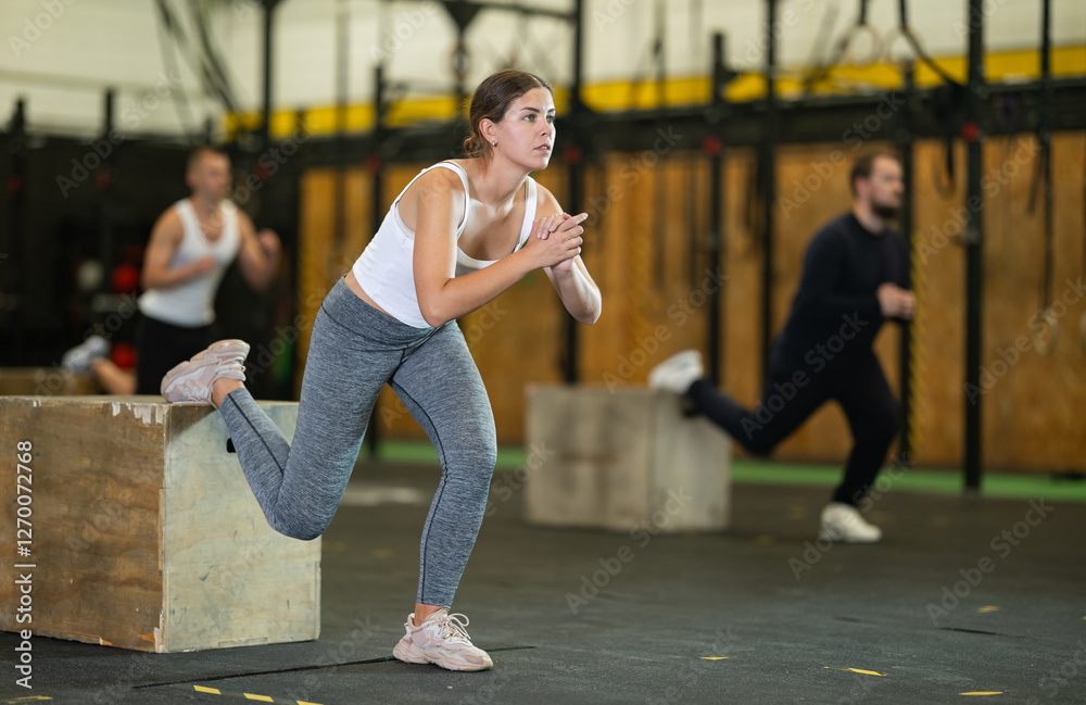 Concentrated young girl in fitness attire performing Bulgarian split ...