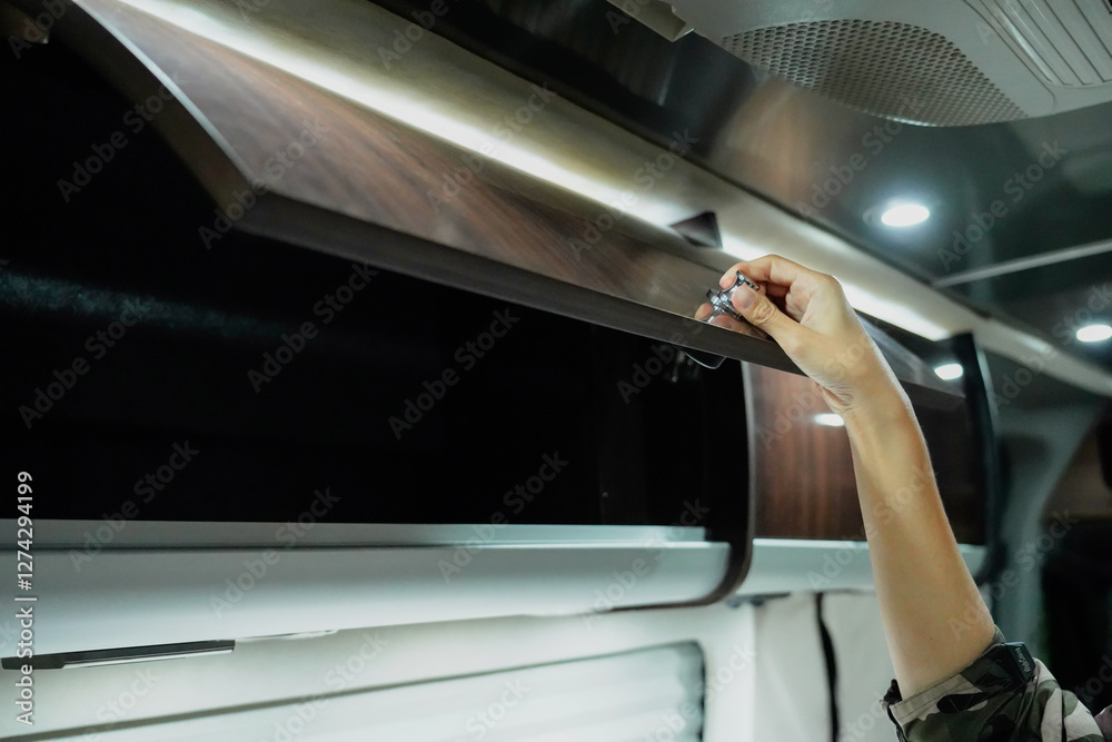 Woman's hand holding a button to opening an overhead wooden cabinet ...