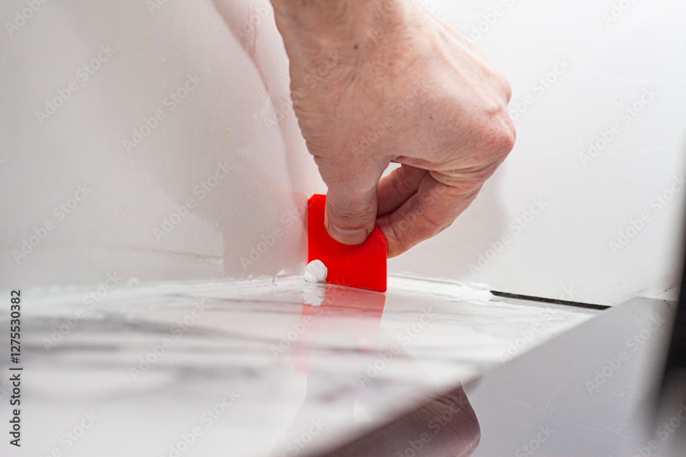 grouting joints with a plastic spatula on porcelain tiles with silicone ...