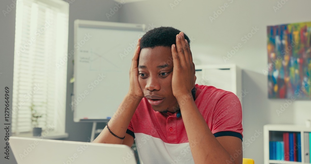 Young dark-skinned boy sits slumped in front of computer, props hands ...