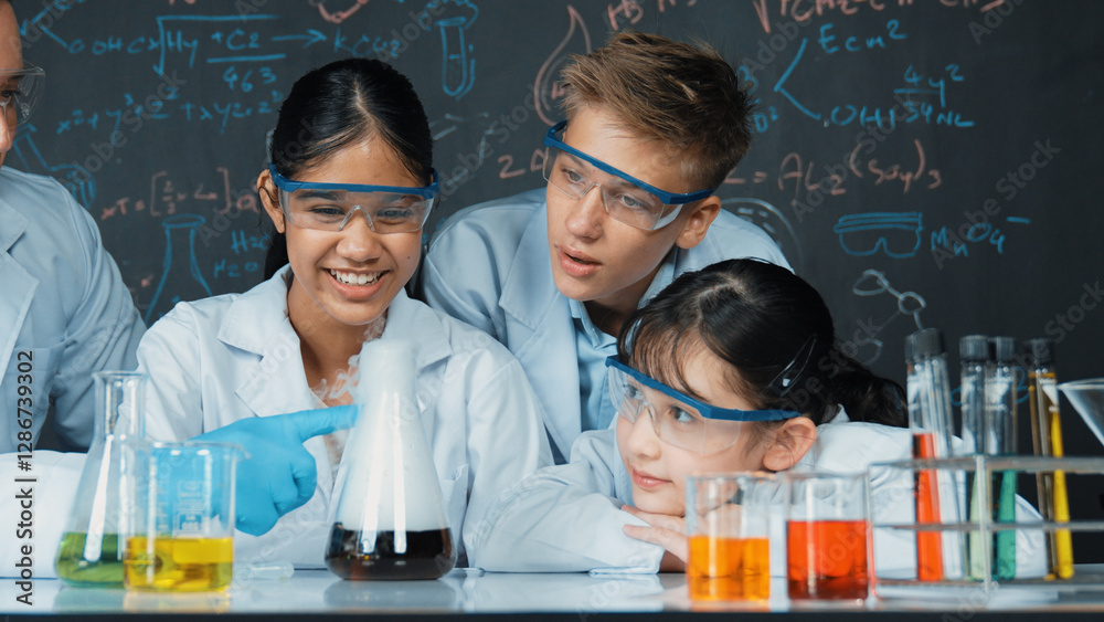 Girl looking at beaker while doing experiment at blackboard with ...