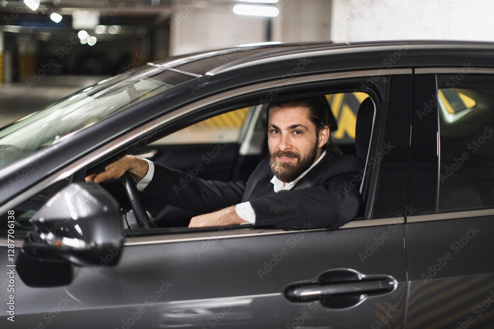 Caucasian man in suit driving car in parking garage. Confident ...
