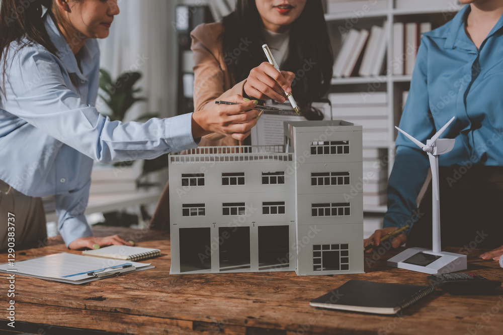 Three engineers are analyzing a building model with a miniature wind ...