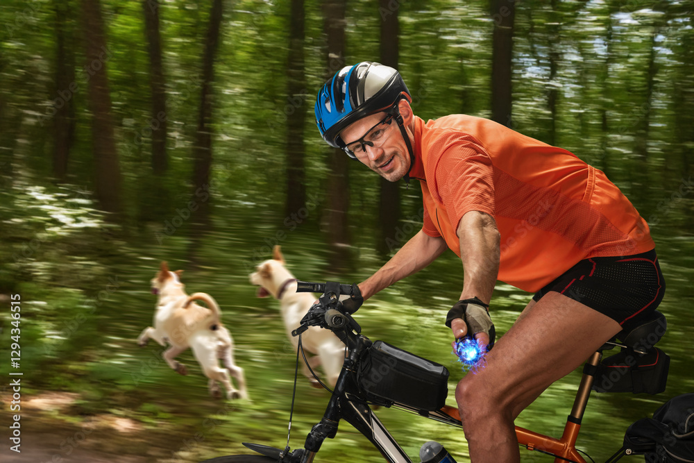 Athletic man riding bike in forest and using taser for protection ...
