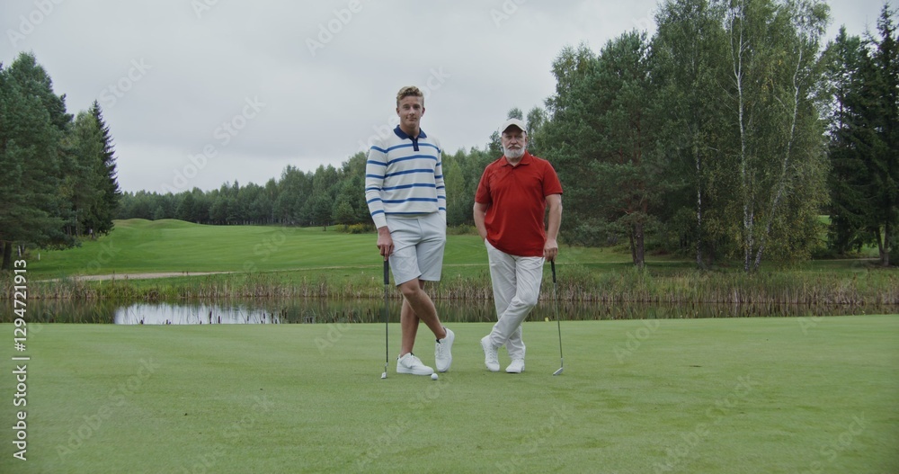 Two men of different ages are standing on the golf course with their ...