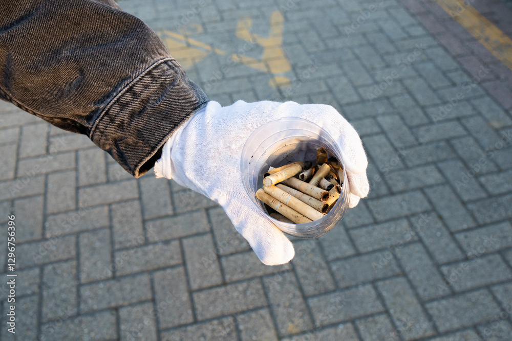 Male hand collecting cigarettes. Cleaning streets from a garbage. The ...