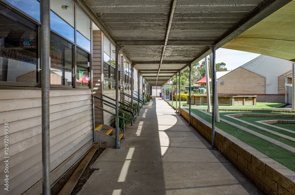 A covered concrete walkway running alongside weatherboard classroom ...