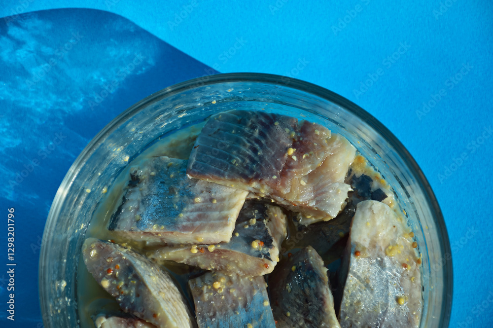 a piece of herring in a glass dish. healthy, salty, fatty fish in oil ...