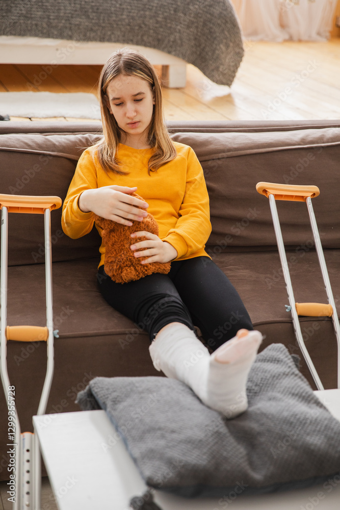 Foto de Stock Young girl with broken leg cast sitting on sofa. Sad ...