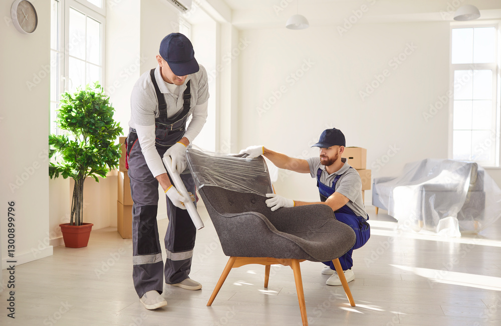 Two professional movers in uniform carefully unpacking and setting up ...