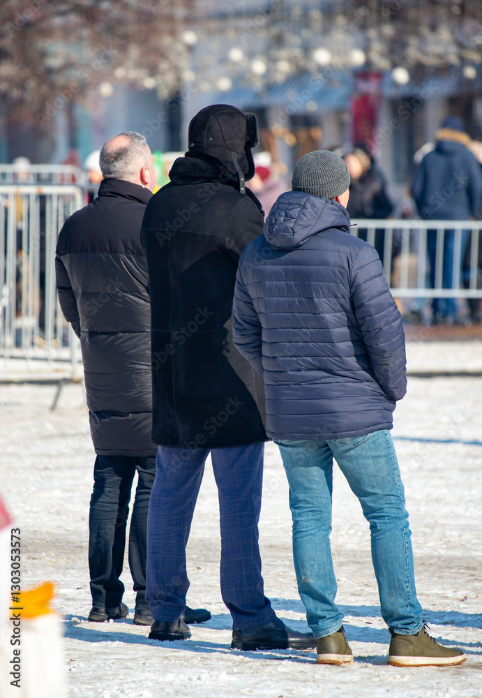 Three men are standing in the snow, wearing black and blue coats Stock ...