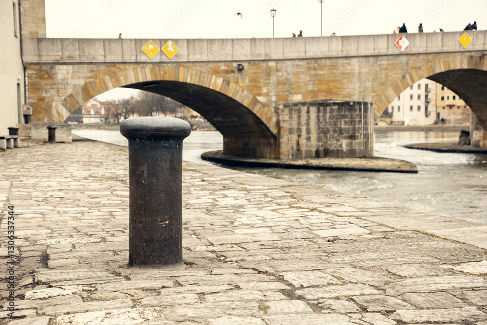 A rustic mooring bollard on an old cobblestone riverbank, with a ...