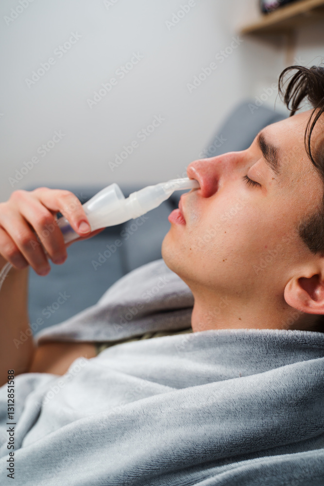Doing nose inhalation with nebulizer at home. Young man with asthma ...
