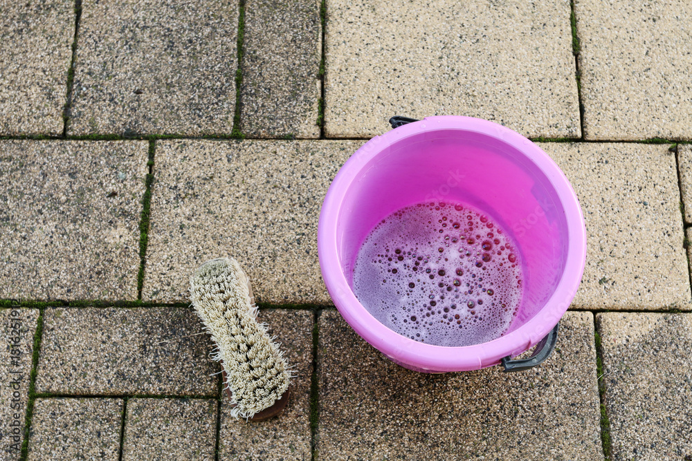 Traditional cleaning of dirty paving stones in the garden with water ...