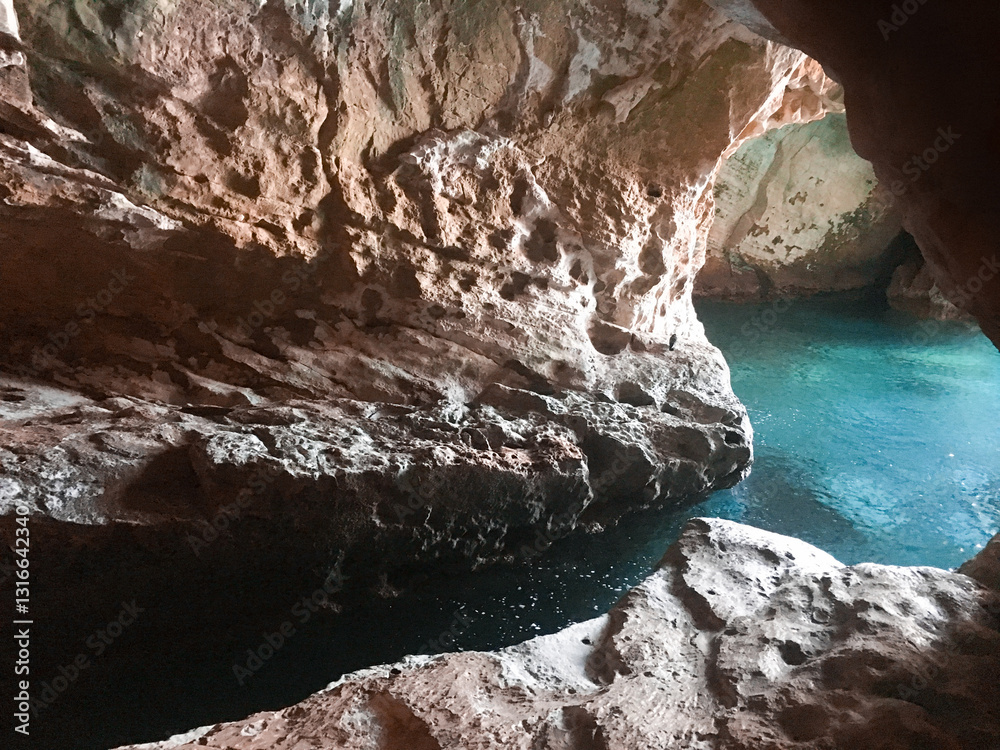 Inside a quiet cave, rugged stone formations twist and rise in uneven ...