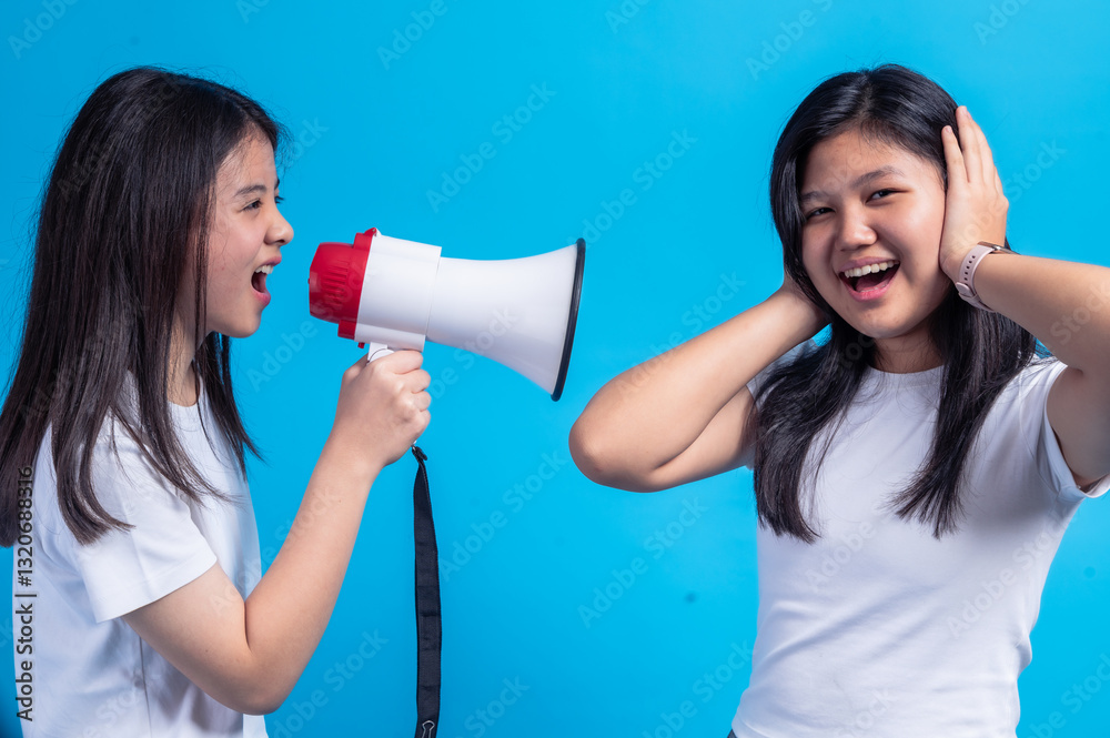 Two Asian teen girls playing with a megaphone, one shouting and the ...