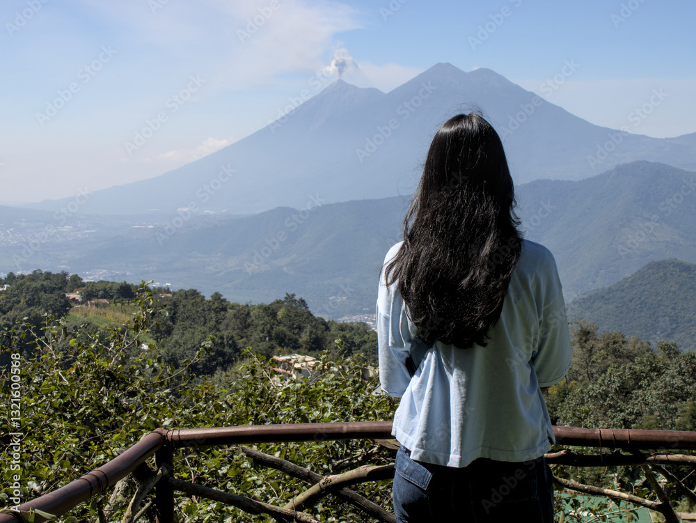 woman with brown hair looking at an erupting volcano in antigua ...