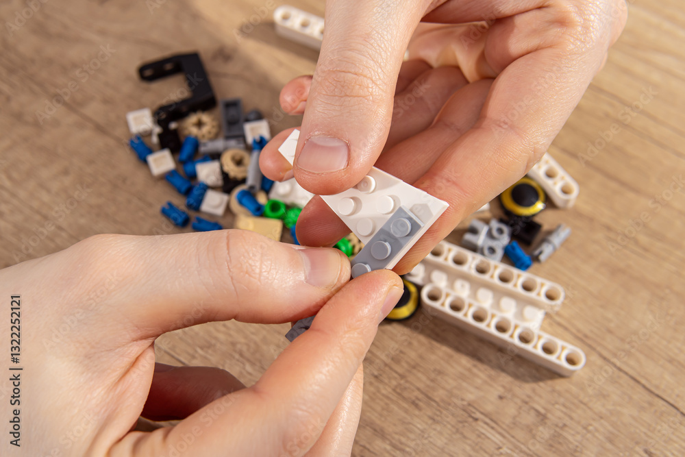 Young man collects the parts of a construction kit. Hobbies for adults ...