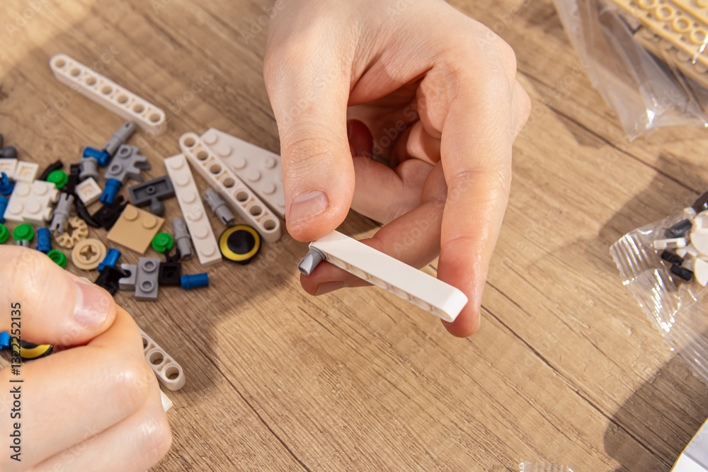 Young man collects the parts of a construction kit. Man connects the ...