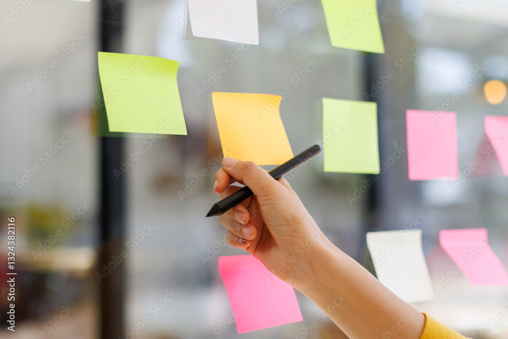 Young asian woman use post it notes to share idea sticky note on glass ...