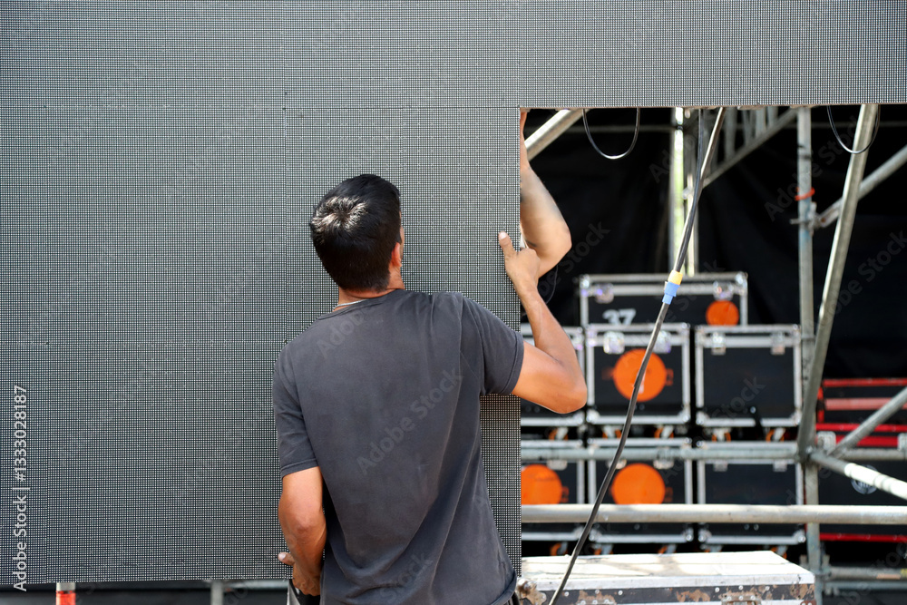 Technicians working on stage assembling giant LED screen panels for ...
