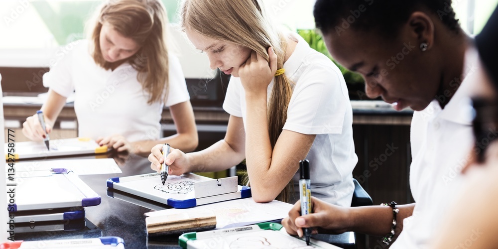 Students focused on drawing in a classroom. Diverse group of young ...