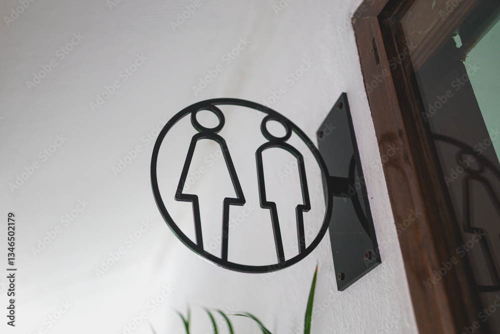 Minimalist black restroom sign mounted on a white wall, featuring ...