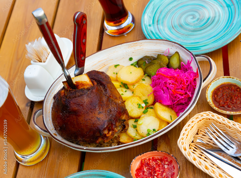 German ham hock with potato, red cabbage and sliced pickled cucumbers ...