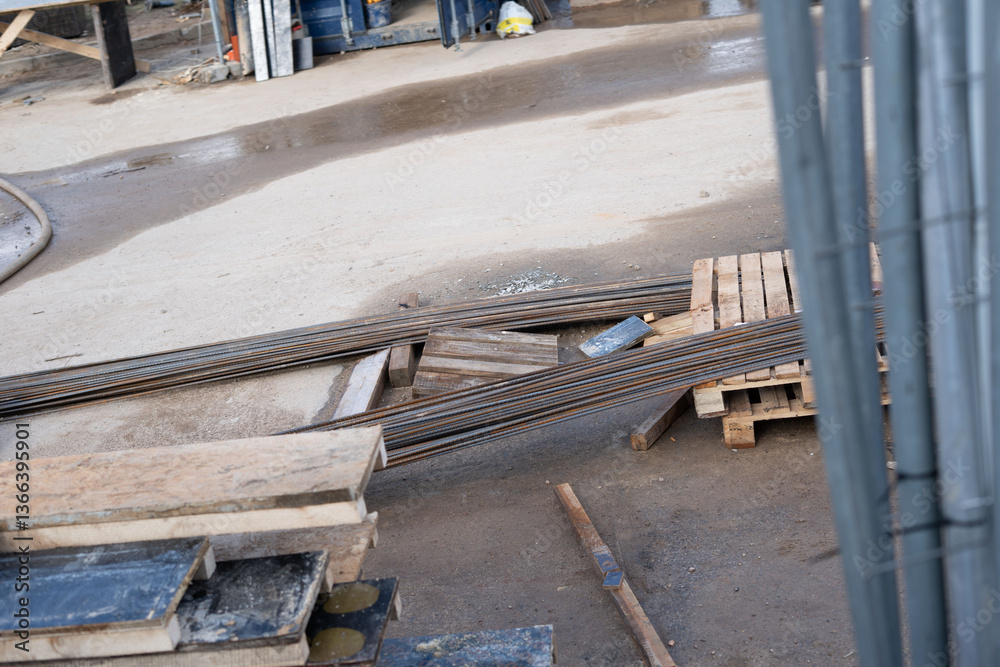 construction site with wet concrete slab, stacked wooden pallets, steel ...