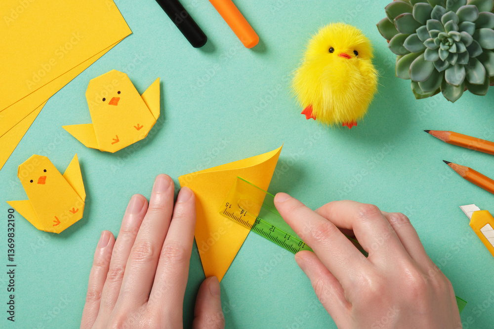 Making a simple Easter origami handicraft. Hands fold a square yellow ...
