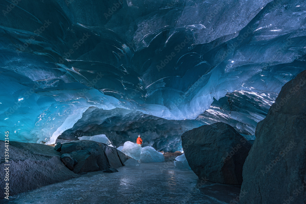 Inside of an ice cave with a person in red cloth showing the scale of ...