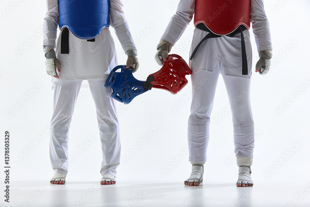 Cropped image of two taekwondo fighters holding red and blue helmets ...